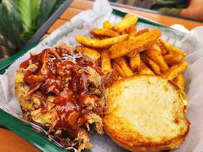 A pulled pork sandwich drowning in Klepto sauce alongside seasoned fries. Sharing this is entirely optional and honestly not recommended.