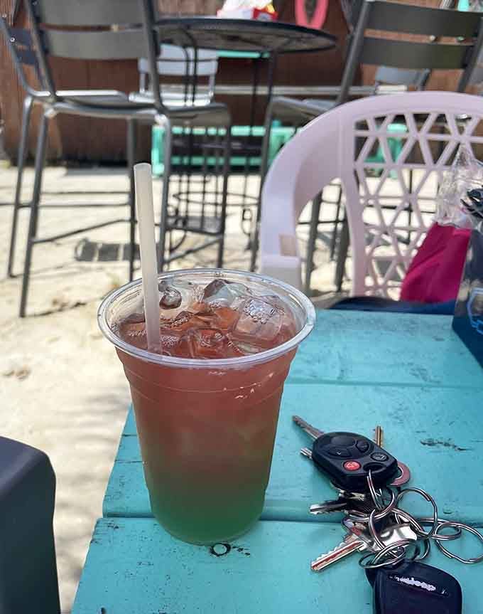 Layered colors, a straw, and sandy tables nearby, this Three Way cocktail is already living its best life.