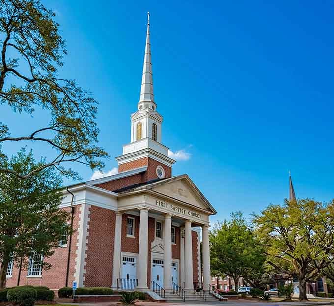 That steeple reaching toward a brilliant blue sky like it's trying to win a height competition with the live oaks.