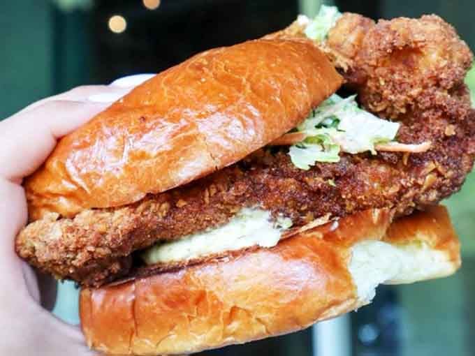 That golden brioche bun barely contains the crispy grouper inside, and honestly, nobody's complaining about the overflow.