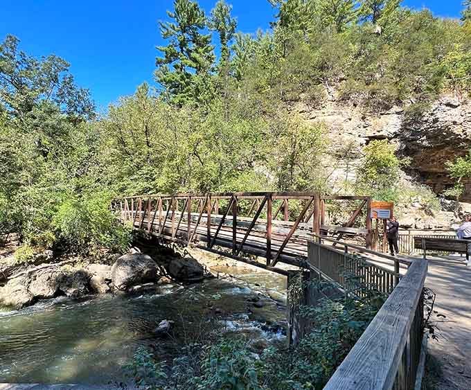 A sturdy truss bridge spans the rushing river below towering sandstone bluffs, connecting trail to trail like nature's own welcome mat.