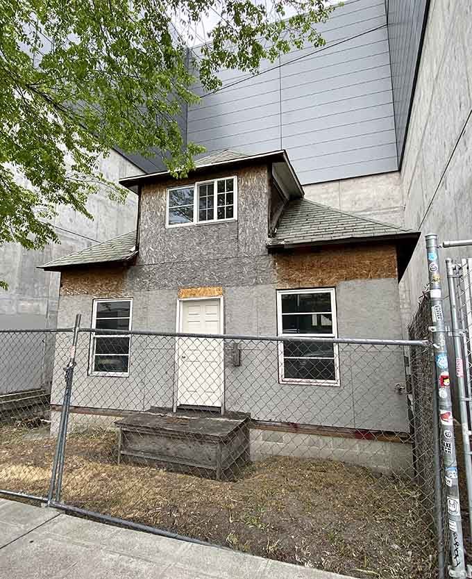 Sandwiched between towering modern buildings, this small weathered house behind a chain-link fence quietly wins the most inspiring standoff in Seattle's history.