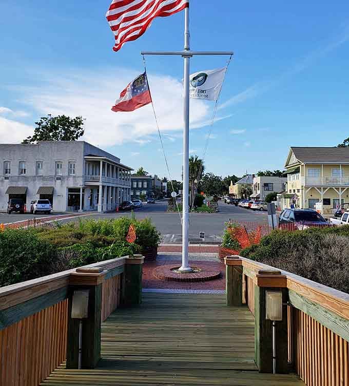 Three flags flying proud over the waterfront pier mark the gateway to coastal adventures and salt-kissed breezes that heal.