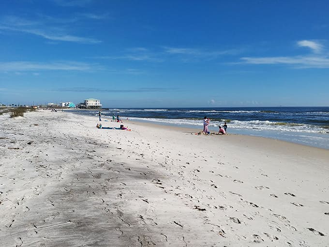 Families dot the pristine shoreline like scattered seashells, each claiming their own piece of coastal heaven for the day.