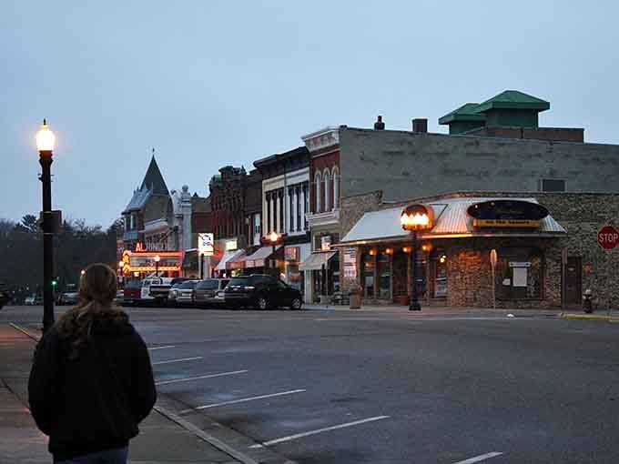 Dusk settles over a main street where the glow from shop windows feels warm and inviting.