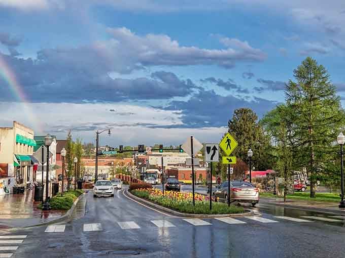 A vibrant rainbow stretches across the sky, brightening up this wet downtown street filled with colorful spring tulip flowerbeds.