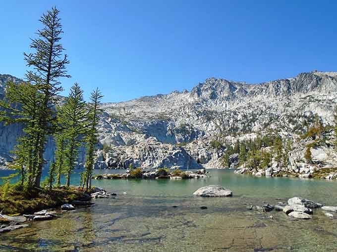 Crystal-clear water reveals every smooth stone below, while jagged peaks remind you exactly how small and lucky you are.