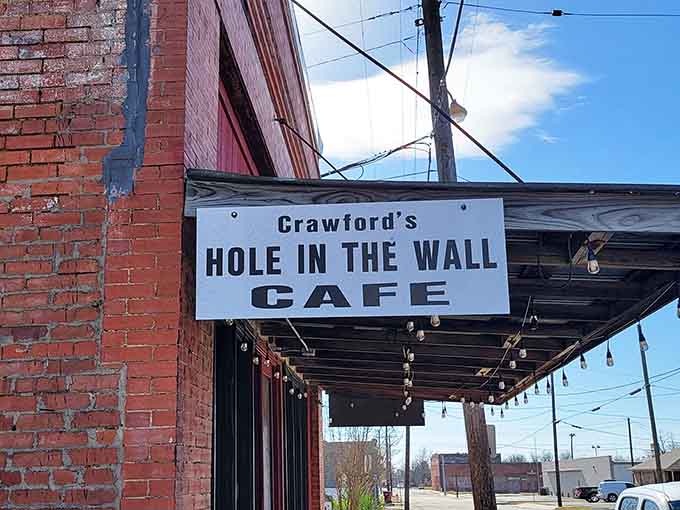 That simple wooden sign reading "Crawford's Hole in the Wall Cafe" hanging under the awning is an honest name for a genuinely great spot.