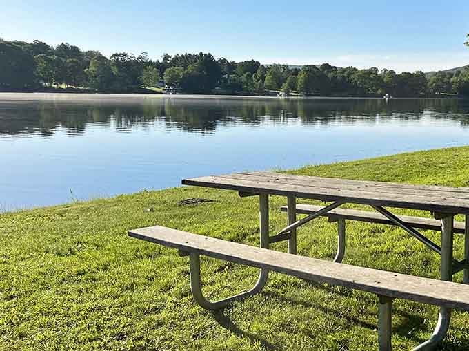 A lone picnic table overlooks Lake Waramaug's mirror-still morning water — the world's most underrated breakfast reservation.