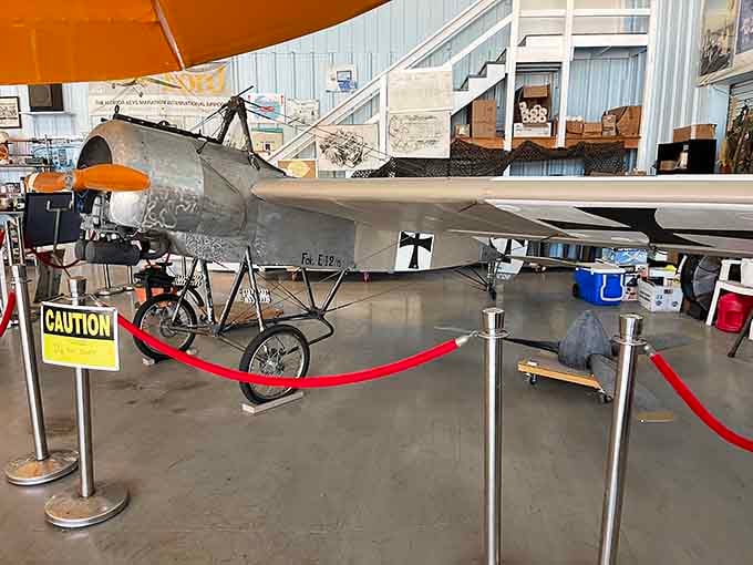 A WWI-era Fokker Eindecker replica sits behind a red rope, looking like it just landed from 1916 and forgot to leave.