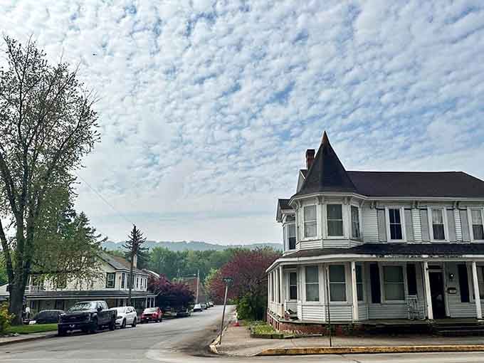 A pointed turret crowns this white Victorian corner house in Marietta, standing tall against a sky full of dramatic, rolling clouds.