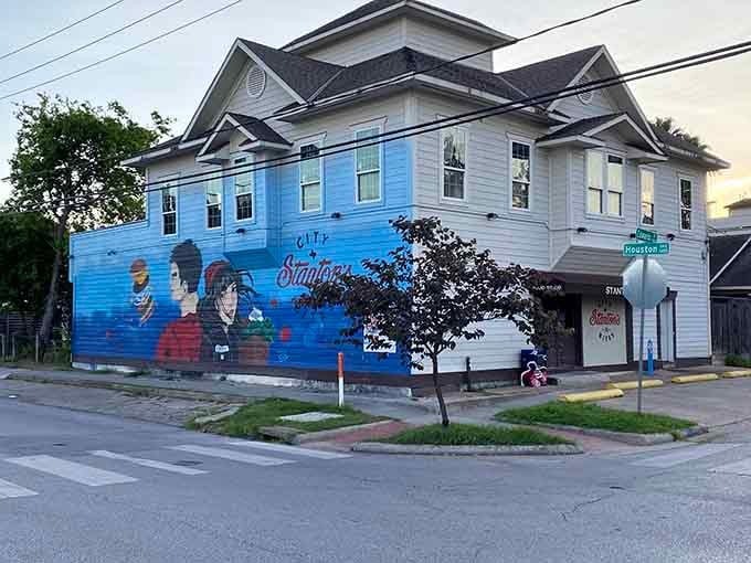 A vivid corner mural splashed in blue, featuring retro figures and fresh ingredients, turns this Houston burger spot into a neighborhood landmark.