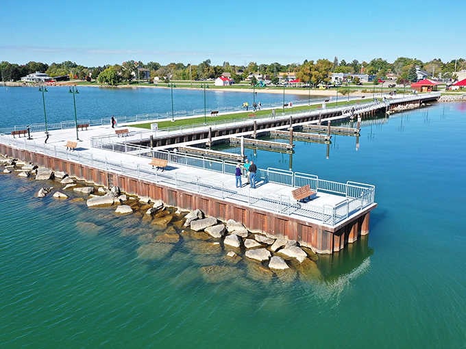 Tawas City's stunning pier reaches out over emerald-green water, where a couple stands fishing and the whole scene looks like pure Michigan poetry.