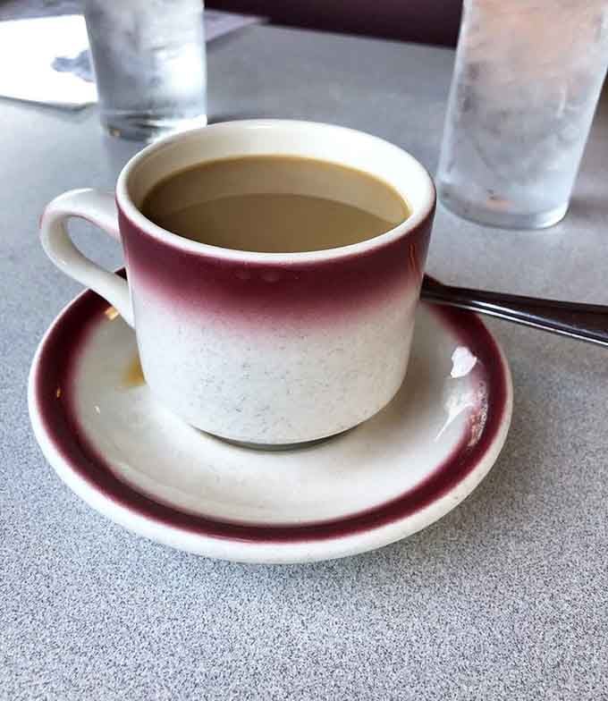 That ceramic coffee cup with its deep burgundy rim is the universal symbol for everything is going to be just fine.