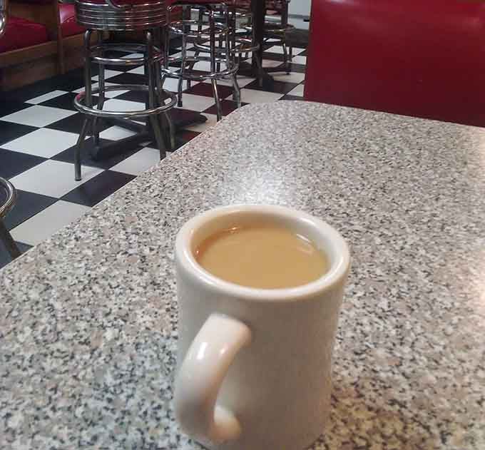 A classic diner mug of coffee with checkered floors behind it &mdash; mornings were made for this.