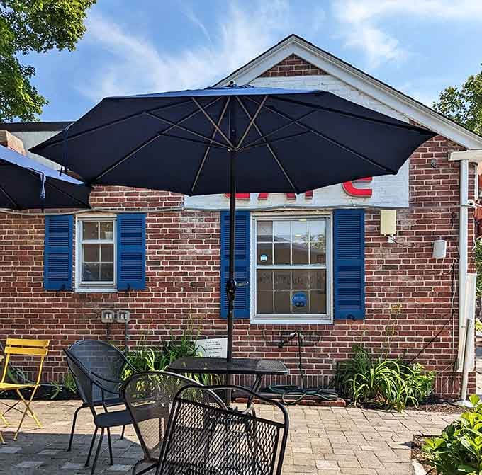 Charming brick cottage with blue shutters and umbrella-shaded tables perfect for lingering over coffee and conversation.