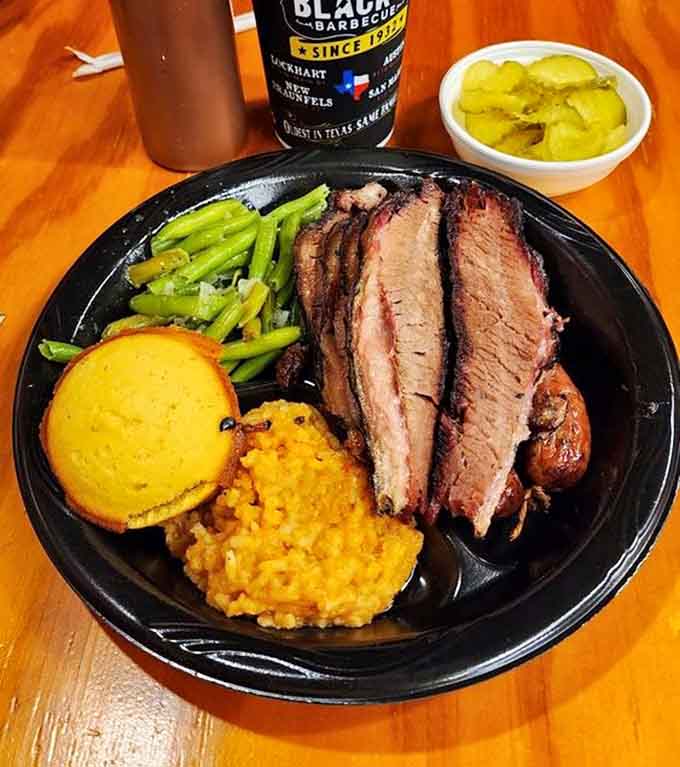 Brisket, sausage, green beans, rice, and cornbread on one plate. Somewhere, a nutritionist is crying. Everyone else is thrilled.
