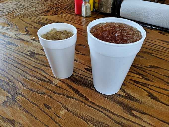 Two foam cups, one small and one large, sitting on a wooden table like old reliable friends who never let you down.