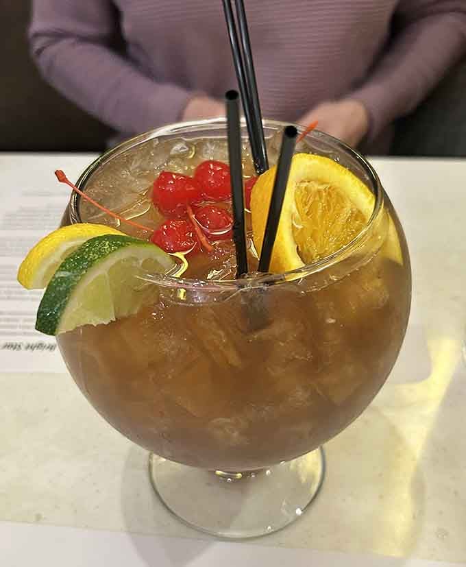 That fishbowl drink arrives dressed for a party, cherries, citrus, and two straws, because some things are just more fun oversized.