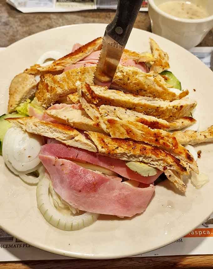 Grilled chicken and ham piled high on a salad, proof that lunch here means serious business.