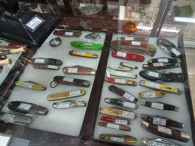 A flat case full of vintage pocket knives, each one labeled and ready to tell a story about where it's been.