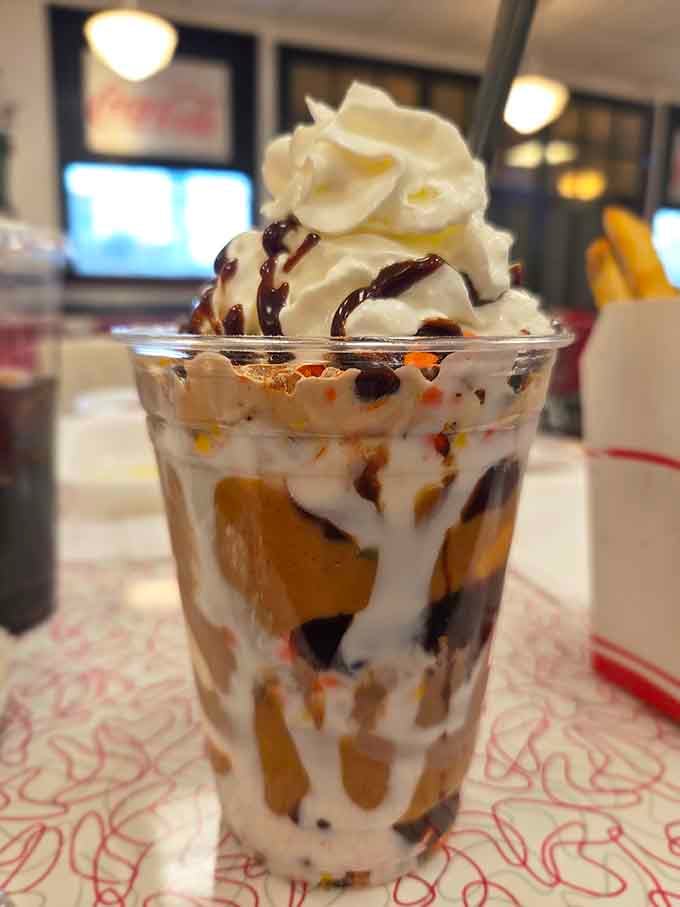 Reese's Pieces, chocolate drizzle, whipped cream, and ice cream layered together. This sundae has absolutely no regrets whatsoever.