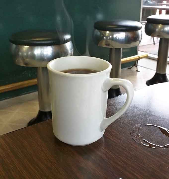 A steaming white mug of coffee with chrome stools in the background. This is what mornings were meant to be.