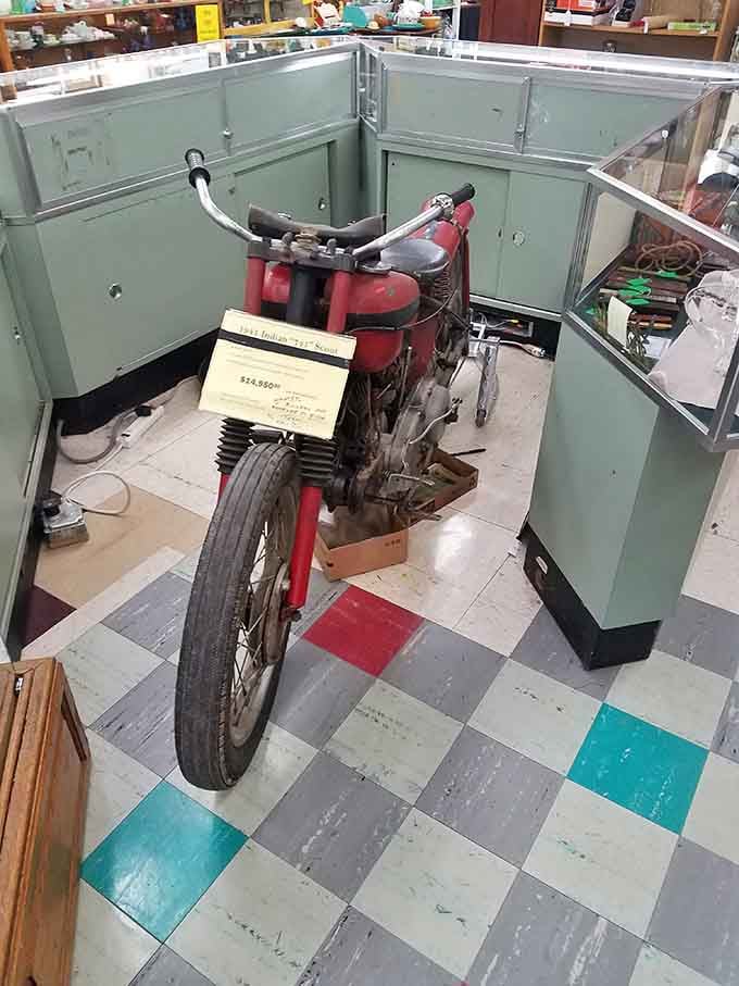 A vintage Indian Scout motorcycle parked right on the showroom floor, casually stealing everyone's attention without even trying.