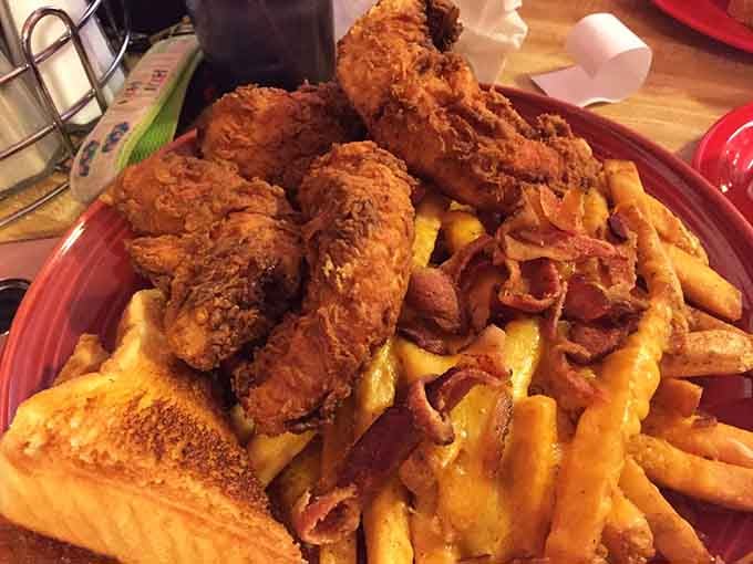 A mountain of crispy chicken tenders over cheese fries and bacon. This plate does not apologize for itself.