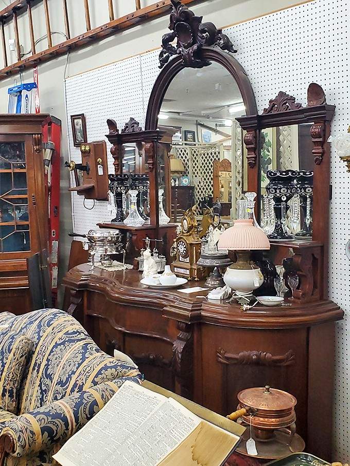 An ornate carved credenza topped with lustres, clocks, and porcelain, basically a greatest hits album of Victorian decorating.