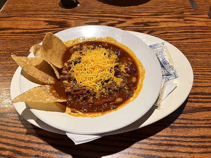 A hearty chili bowl topped with shredded cheese and served with tortilla chips. This is cold-weather happiness in a bowl.