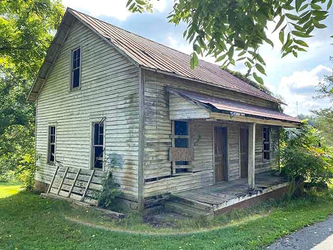Boarded doors and a tilting porch, yet somehow this cottage still stands with quiet dignity.