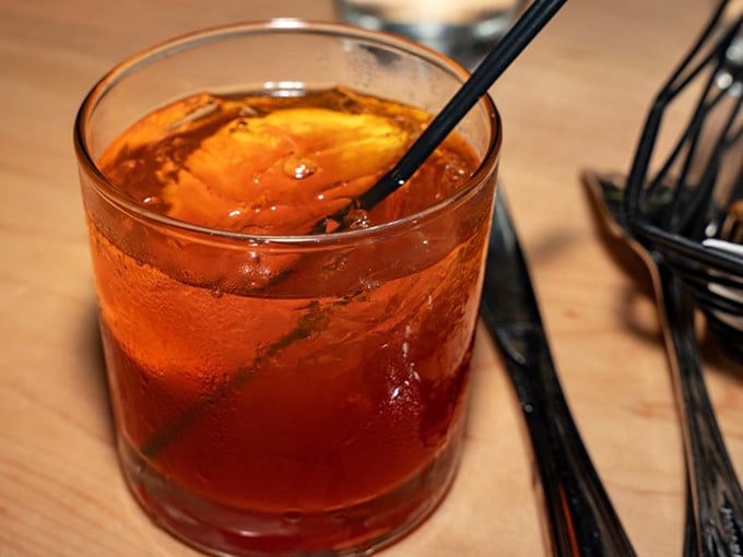A proper old fashioned, amber and ice-cold, sitting next to silverware. The meal hasn't started, but the evening already has.