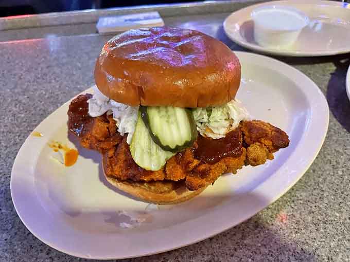 A hot Nashville-style chicken sandwich stacked with pickles, coleslaw, and attitude — this brioche bun is holding on for dear life, and honestly, same.