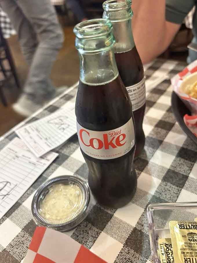 A glass bottle of Diet Coke on a checkered tablecloth, because some meals deserve a little old-school refreshment alongside them.