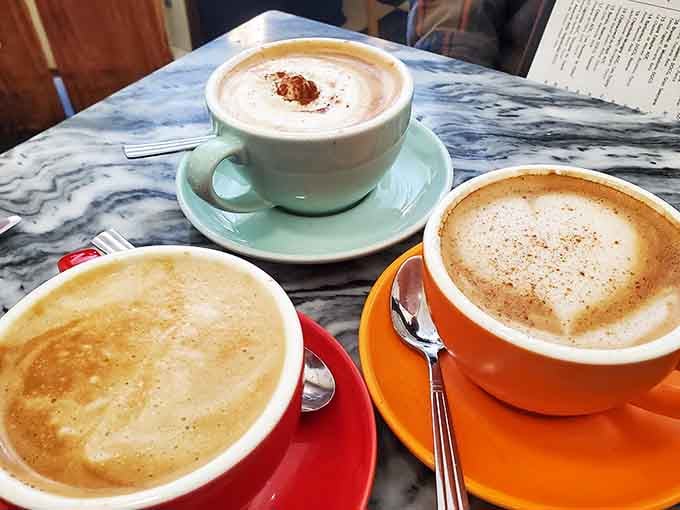 Colorful cups of café au lait lined up like a rainbow of caffeinated happiness on marble perfection.