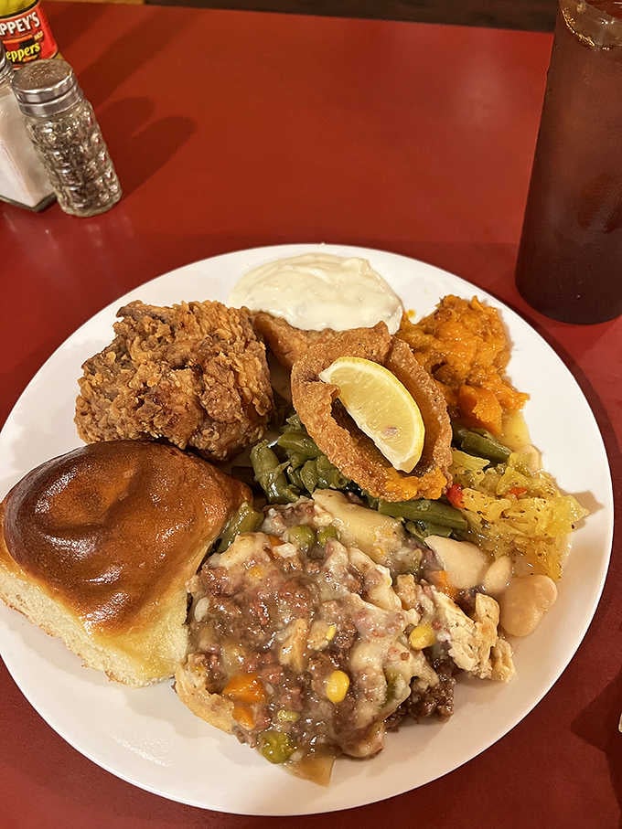Fried chicken, a soft yeast roll, shepherd's pie, and yams all sharing one plate like old friends at a reunion.