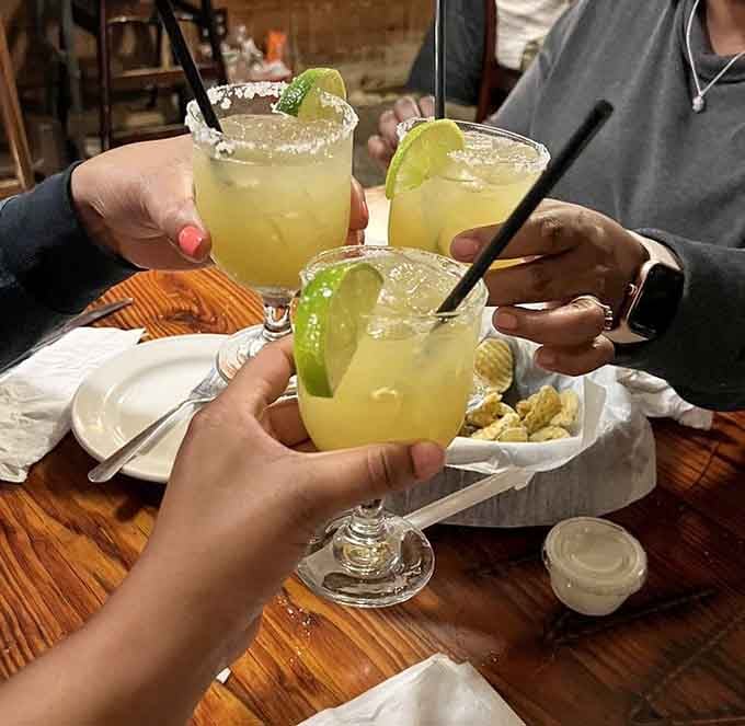 Three margaritas clinking together over a wooden table. Some afternoons simply demand a toast.