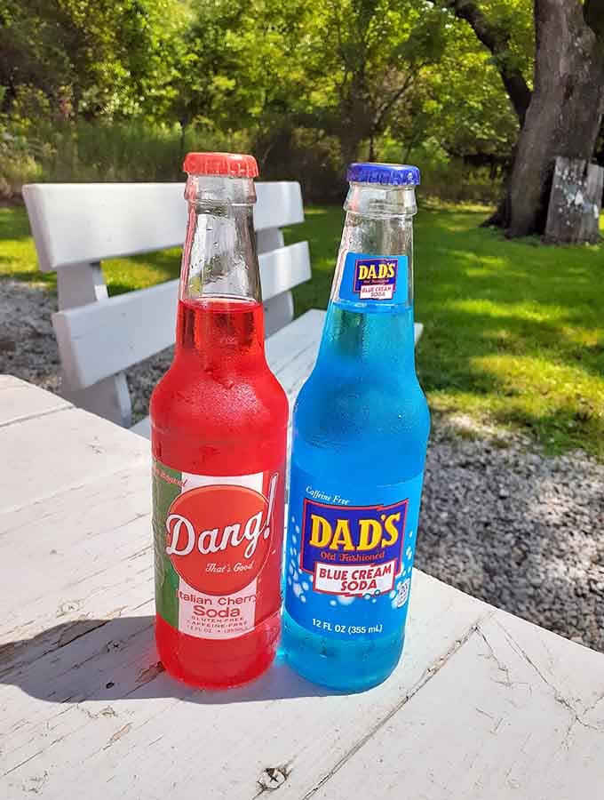 Vintage glass bottles of colorful soda add a nostalgic touch that pairs perfectly with your burger experience.