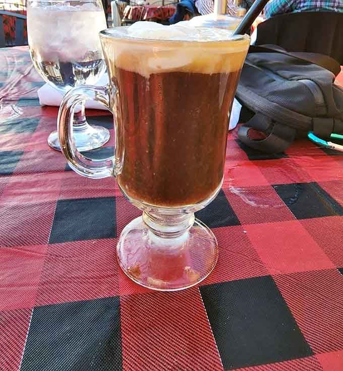 A frothy Irish coffee on a red-checked tablecloth, the kind of drink that makes outdoor dining feel like a warm hug.