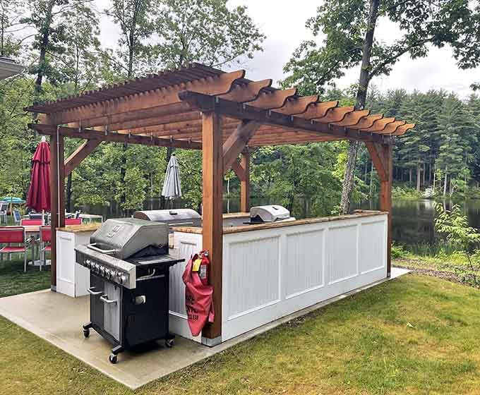 A pergola-covered outdoor kitchen by the water, grilling just got a serious upgrade.