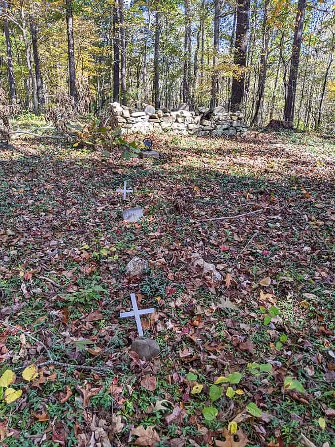 Simple white crosses among autumn leaves, a humble and deeply moving reminder that real people rested here.