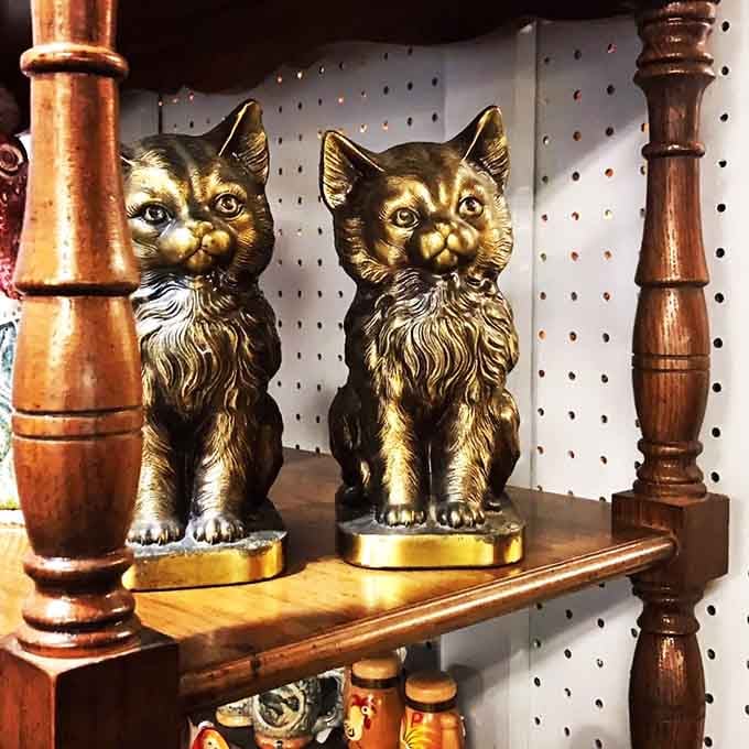 Two brass cats sitting on a shelf, judging every shopper who walks by with quiet, golden dignity.