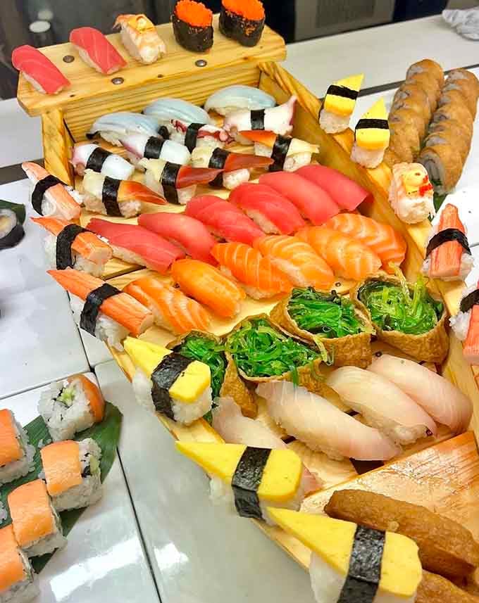 Fresh nigiri arranged on a wooden boat, looking far too elegant for an all-you-can-eat situation.