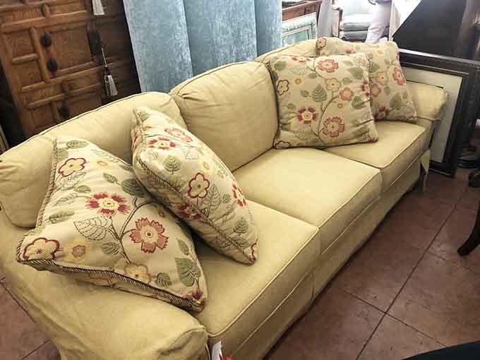 A well-loved sofa with floral pillows that practically whispers, "Sit down, stay awhile, you've earned this."
