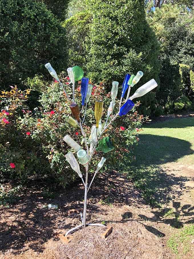 A tree made entirely of colorful glass bottles catching the sunlight, because why plant ordinary when extraordinary is clearly an option?