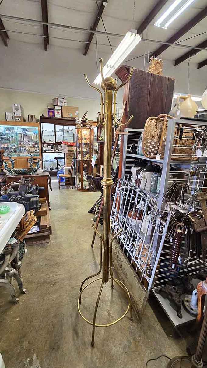 A gleaming brass coat rack standing tall among the treasures, proof that even the functional stuff here has serious personality.