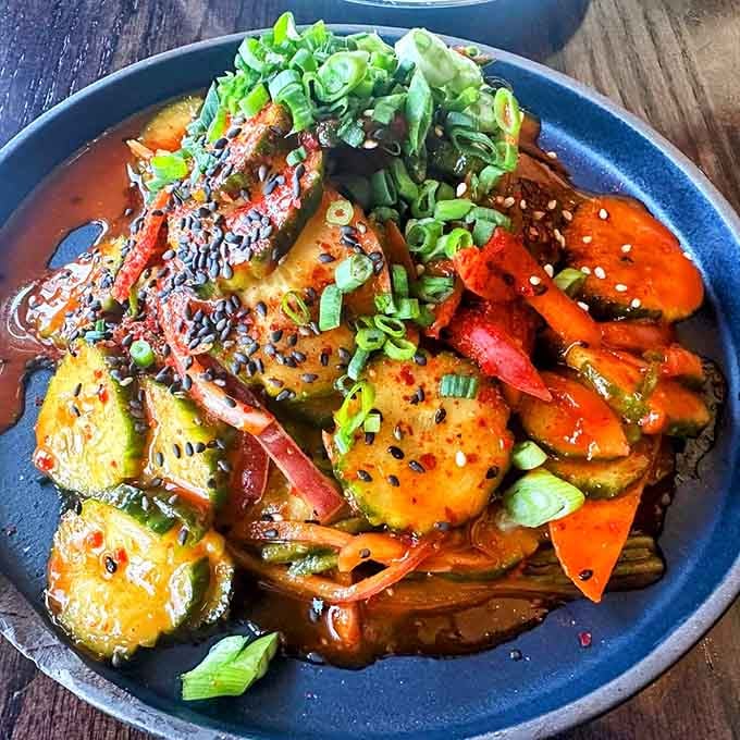 Cucumbers glazed in something deeply savory and spicy, scattered with sesame and scallions. A side dish that steals the whole show.