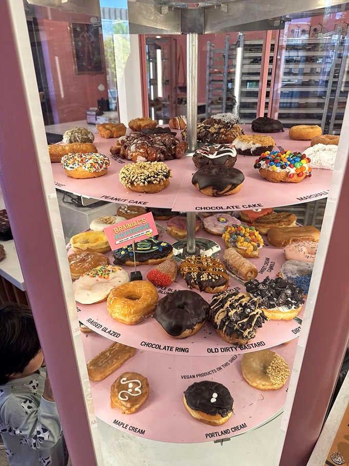 A pink rotating tower of donut specimens, labeled and displayed like sugary works of art.