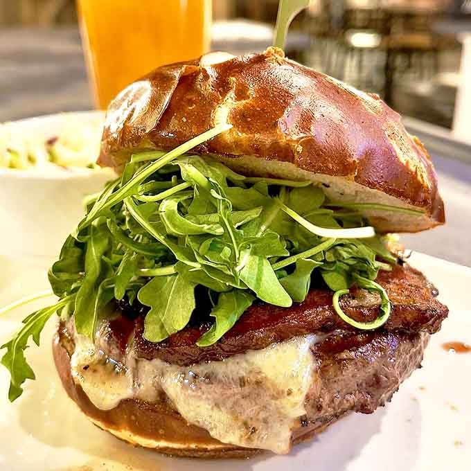 A burger so tall it needs its own zip code. That pretzel bun and arugula situation is absolutely serious business.
